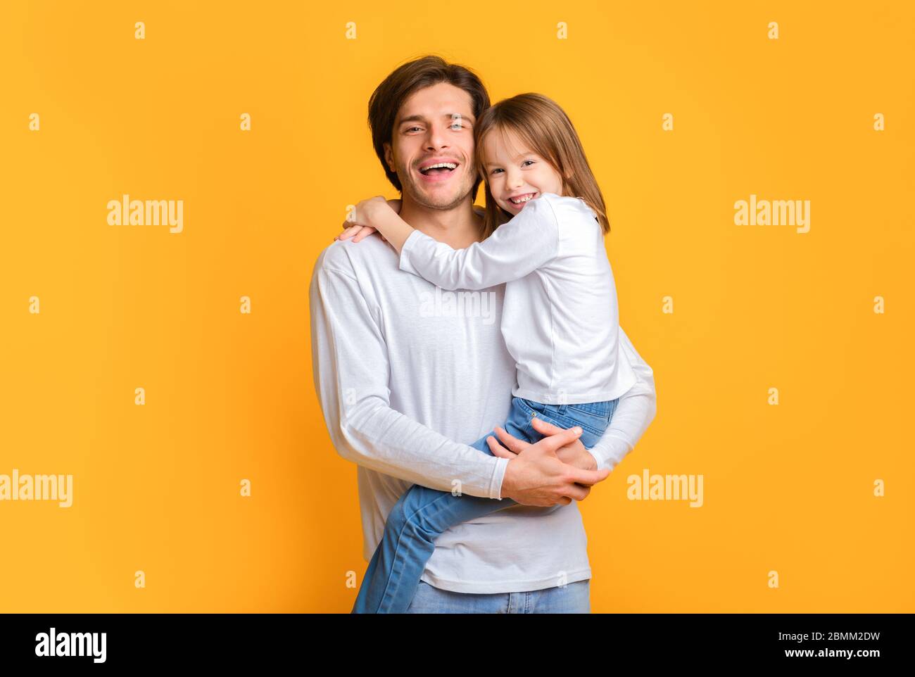 Emotional father and daughter posing together on yellow background ...