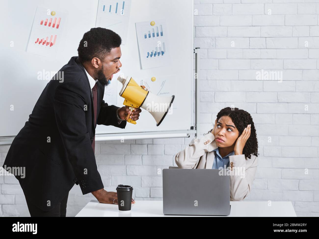 Furious boss with loudspeaker yelling at female subordinate in office ...