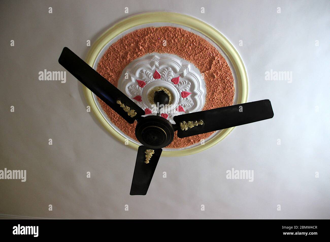 Painted, decorative concrete ceiling and dark brown ceiling fan Stock ...