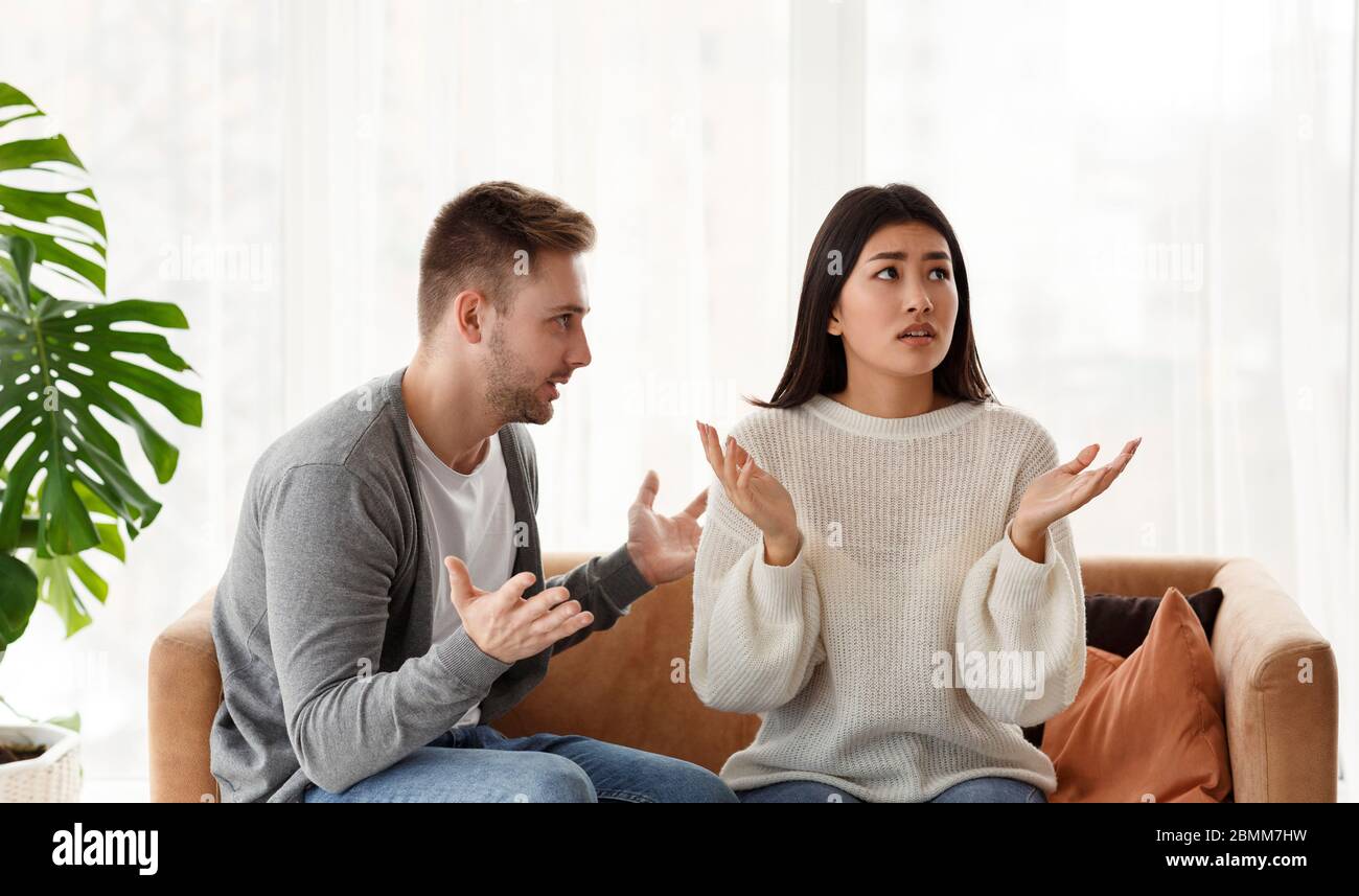 Multiracial Couple Arguing Sitting On Couch At Home During Quarantine ...