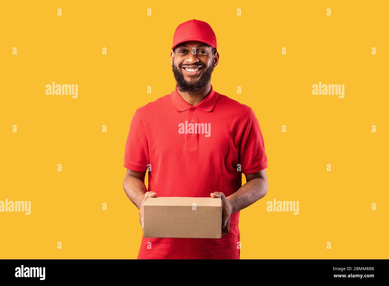 Black Courier Man In Uniform Holding Cardboard Box, Studio Shot Stock ...