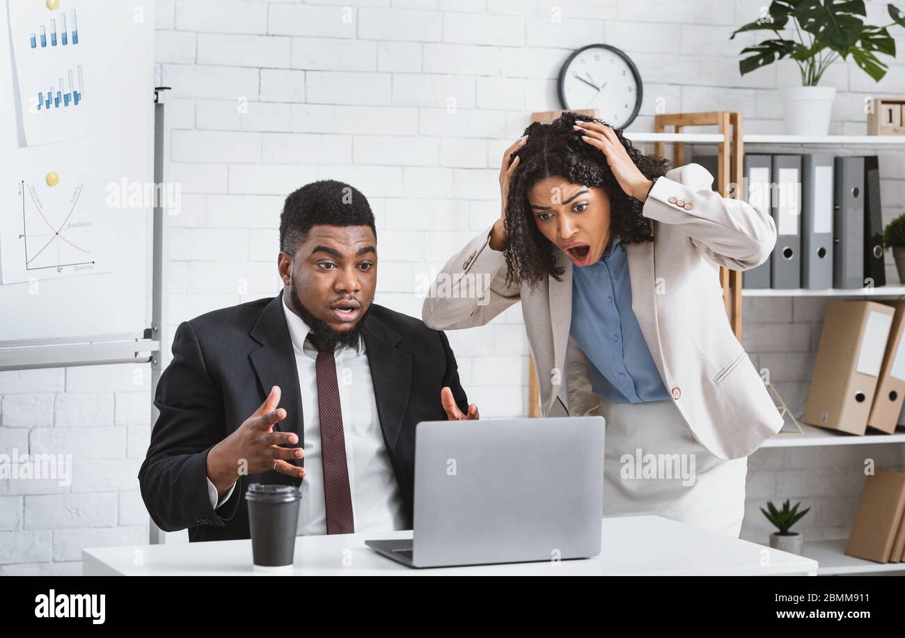 Anxious African American colleagues finding mistake in project or ...