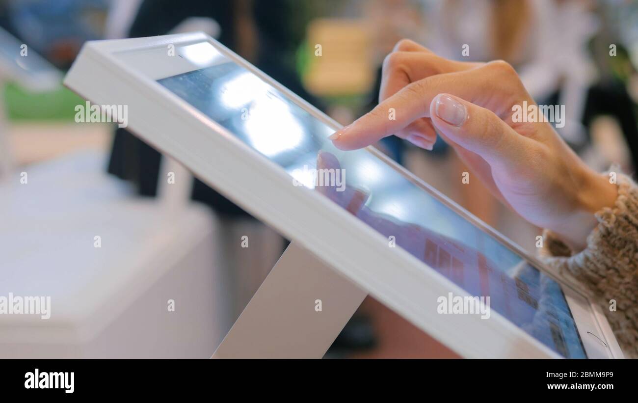 Woman using interactive touchscreen display at urban exhibition ...