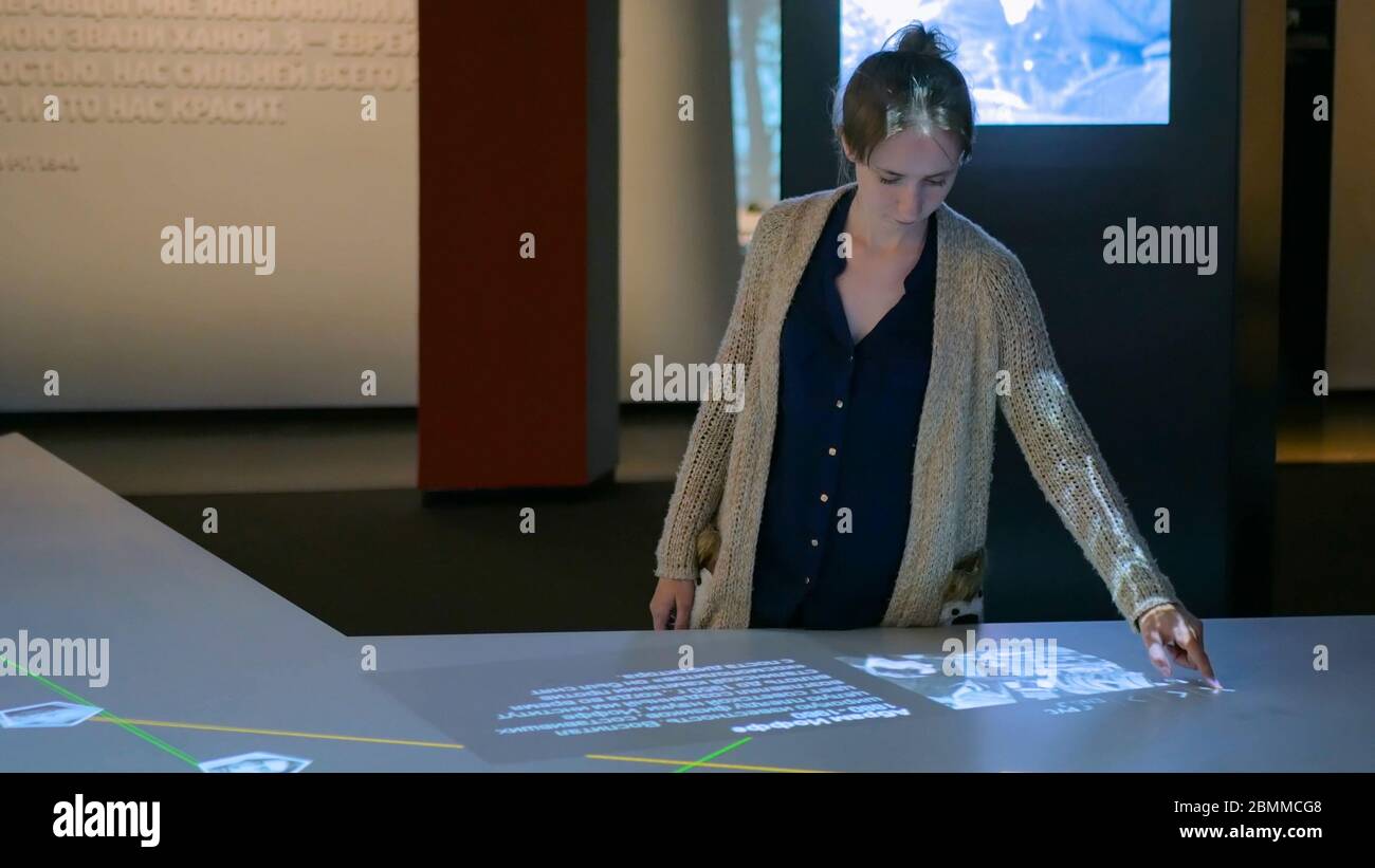 Woman using interactive touchscreen display at modern history museum ...