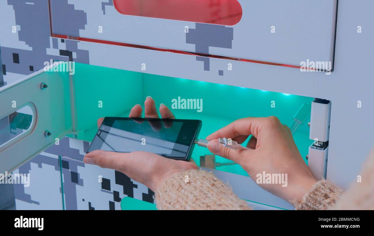 Woman using electronic charging station for charge smartphone battery ...