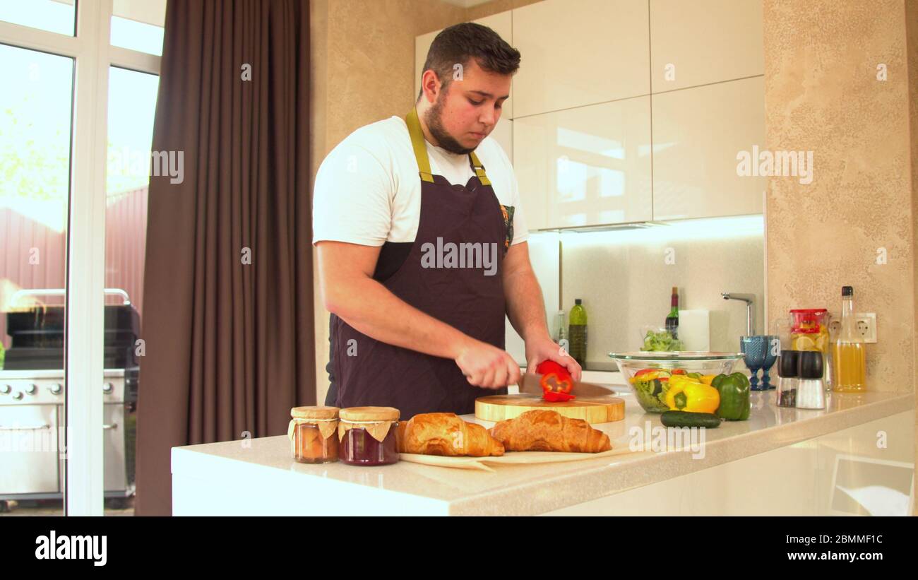 Medium shot of a man cutting yellow bell pepper for salad Stock Photo ...