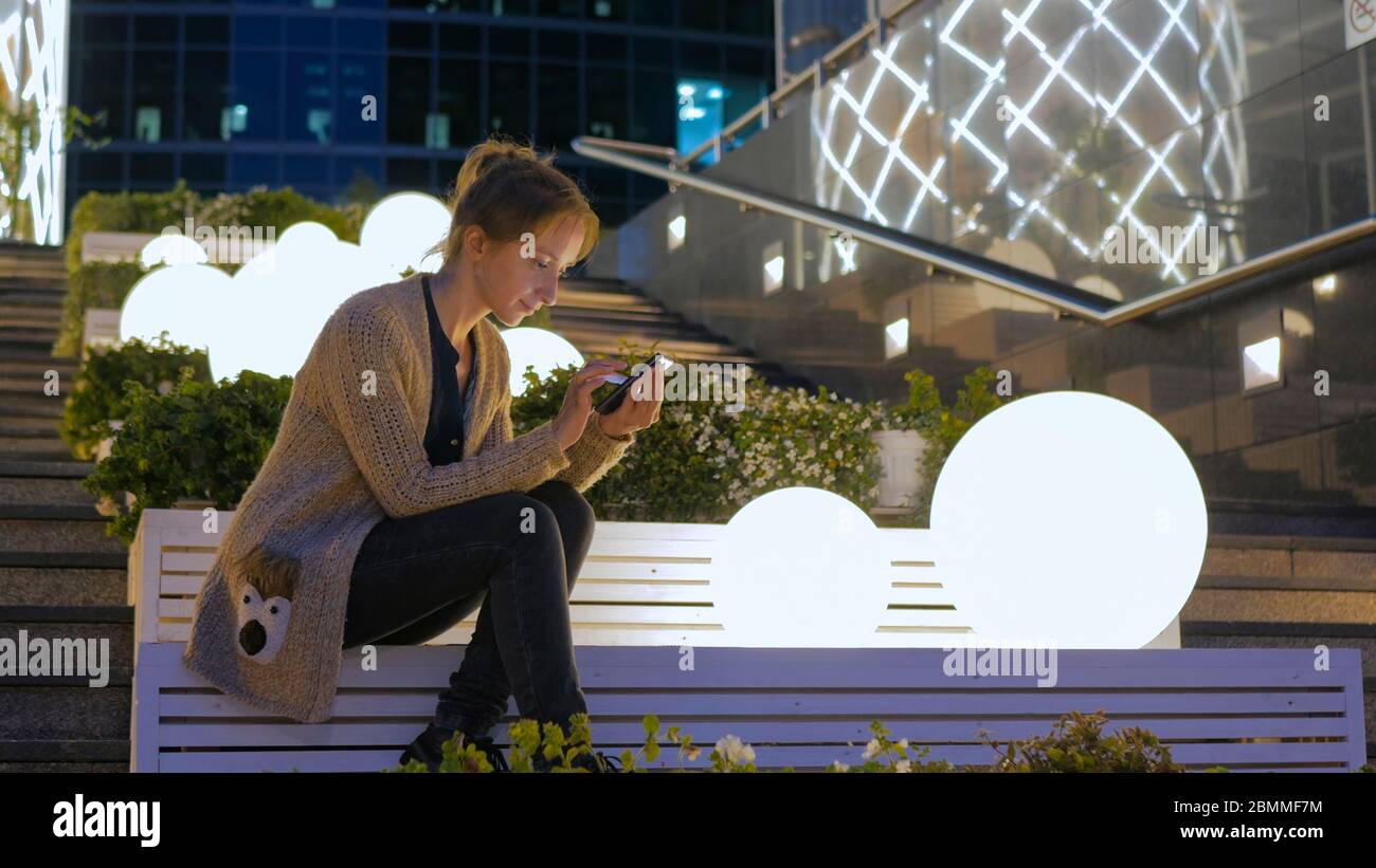 Woman scrolling smartphone night street hi-res stock photography and ...