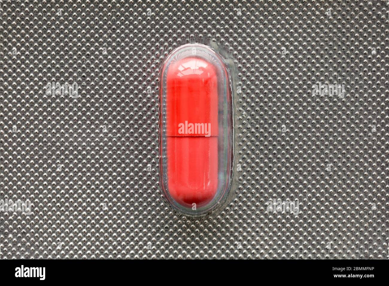 Single red medical capsule in blister, macro, top view, medical concept ...