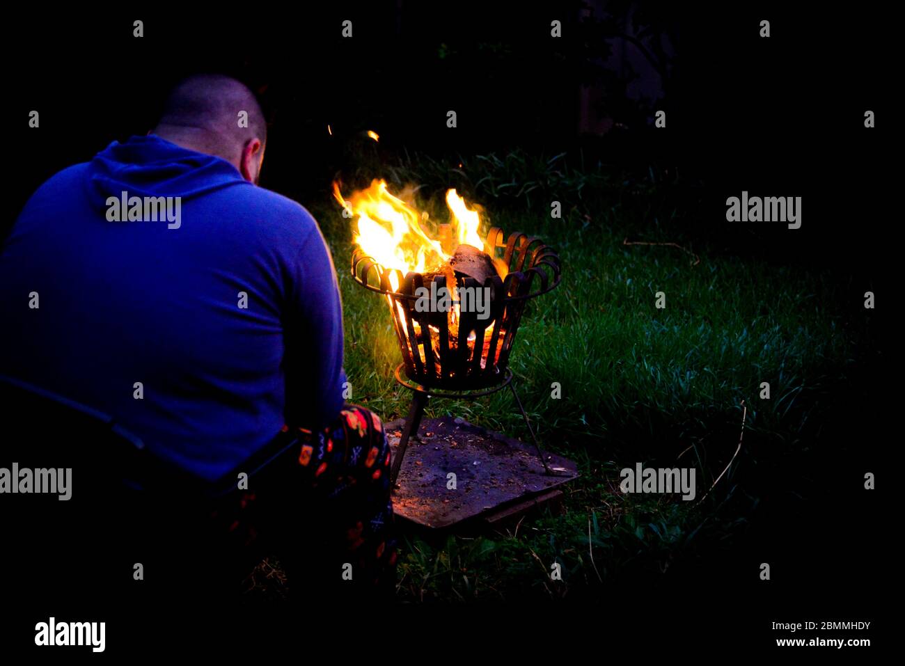 Man Sitting in Backyard in Front of Fire in Dark Stock Photo - Alamy