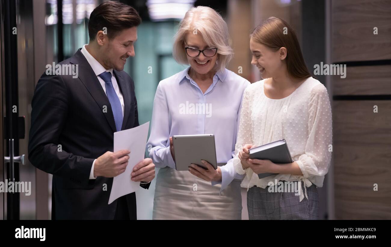 Mature boss and subordinates talking standing in office hallway Stock ...