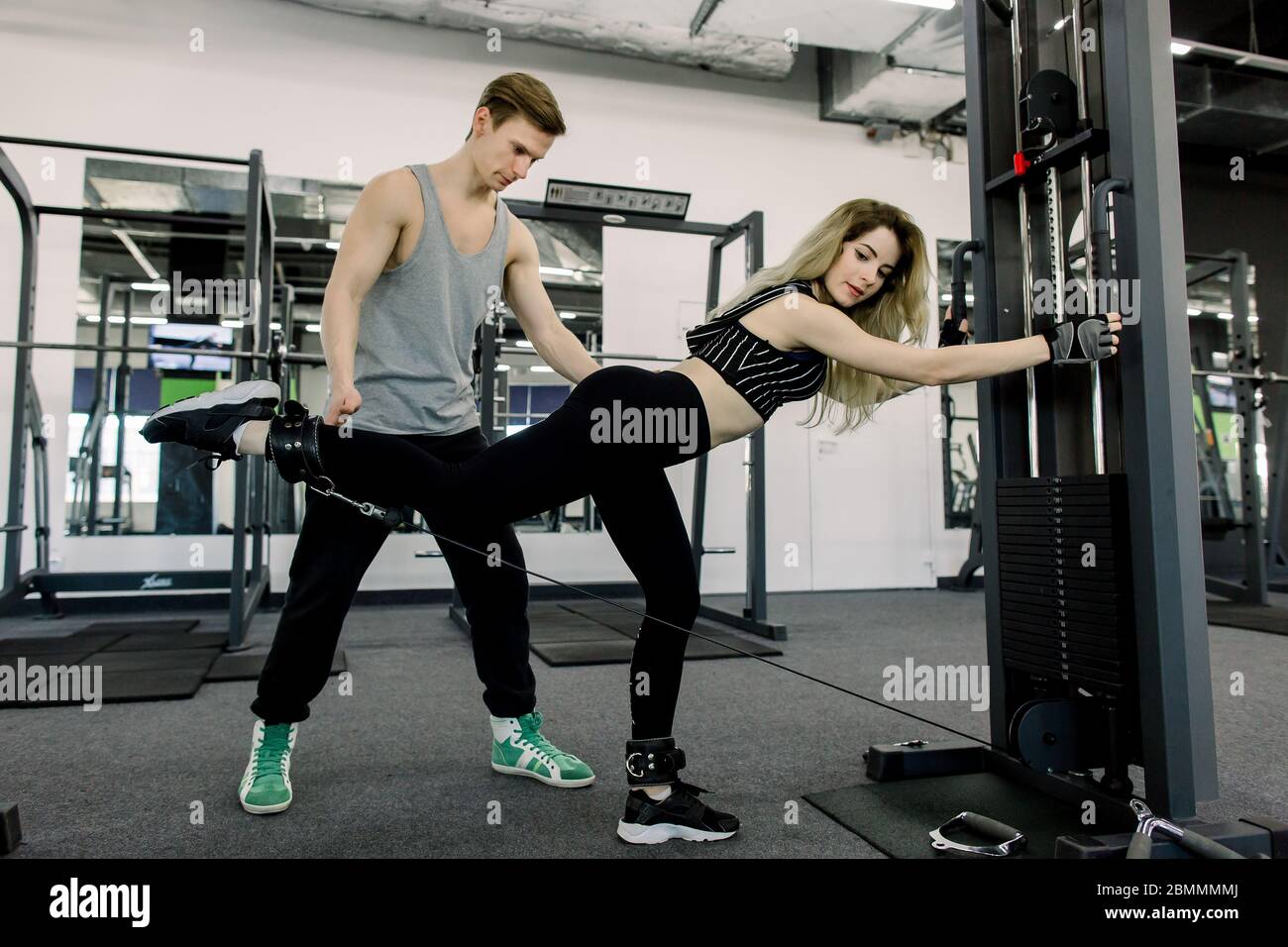 Fitness woman training with her personal trainer at gym. Young couple ...