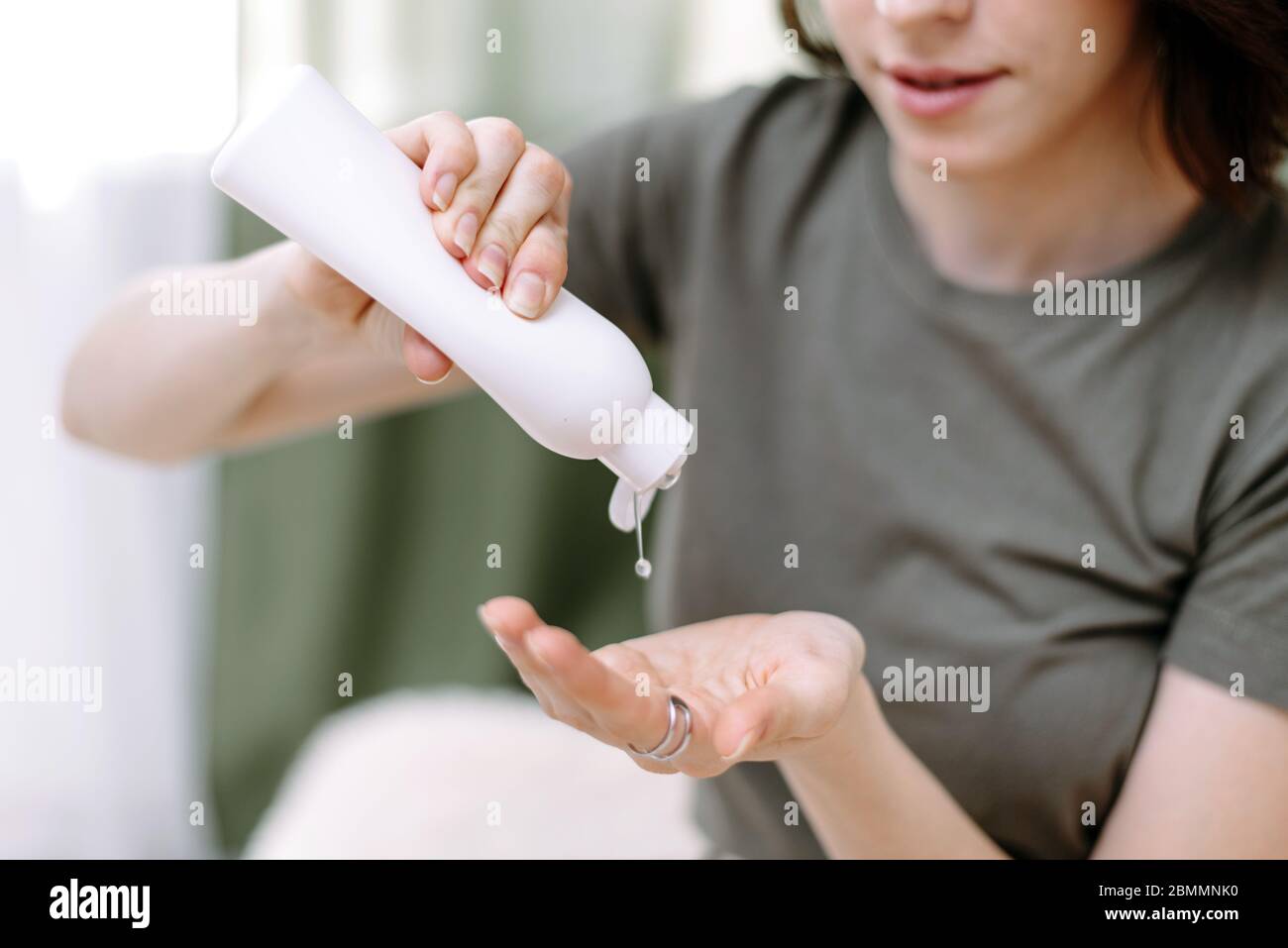 Woman pouring lotion or hand cream from bottle into her hand. Skin care ...