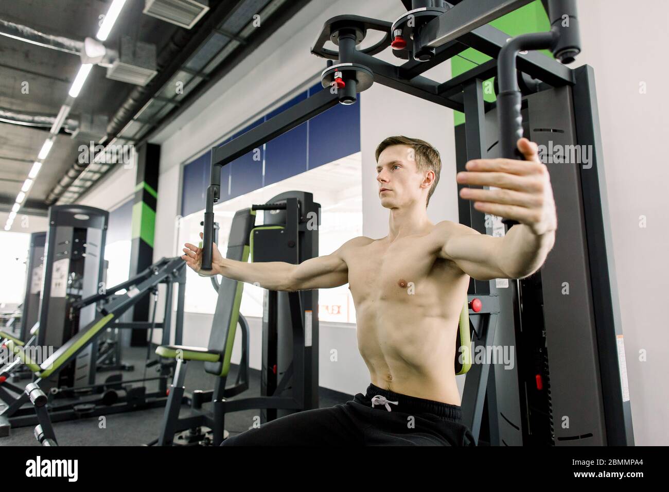 Young man training in the gym. Ripped bodybuilder working out in gym ...