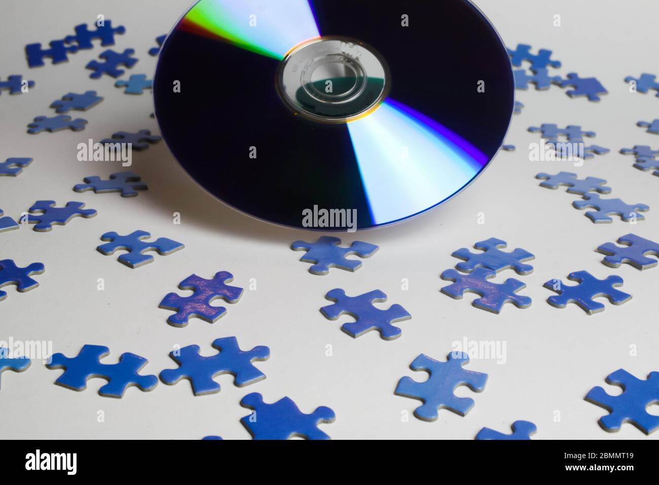 Close up of blue shattered puzzle pieces and DVD storage medium, white ...