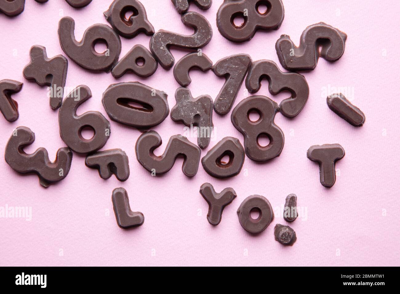 an artsy studio shot of chocolate letters and numbers against a pastel ...