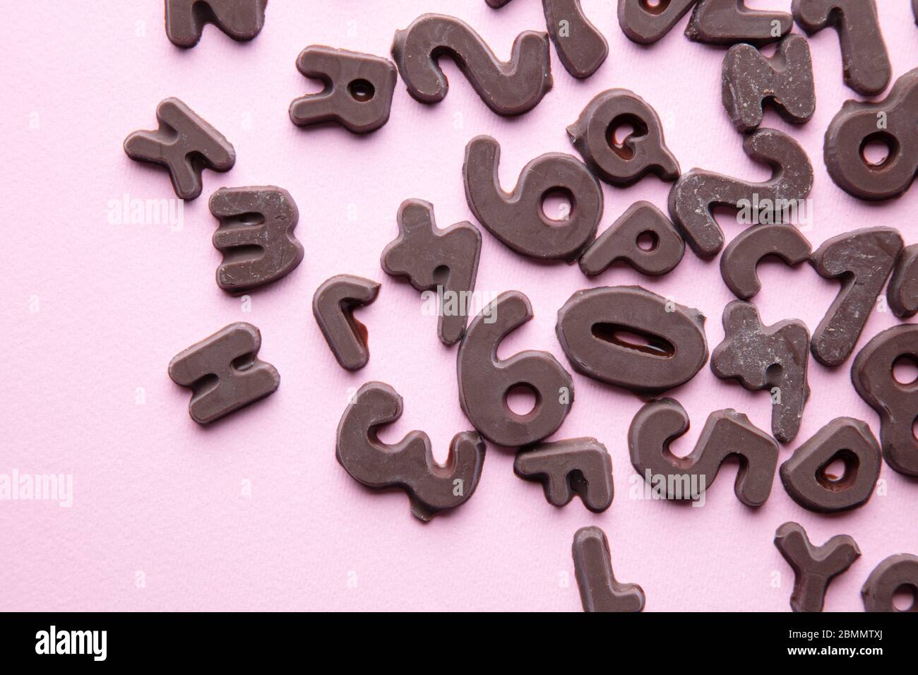 an artsy studio shot of chocolate letters and numbers against a pastel ...