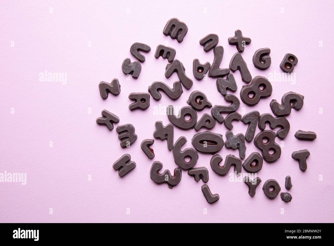 an artsy studio shot of chocolate letters and numbers against a pastel ...