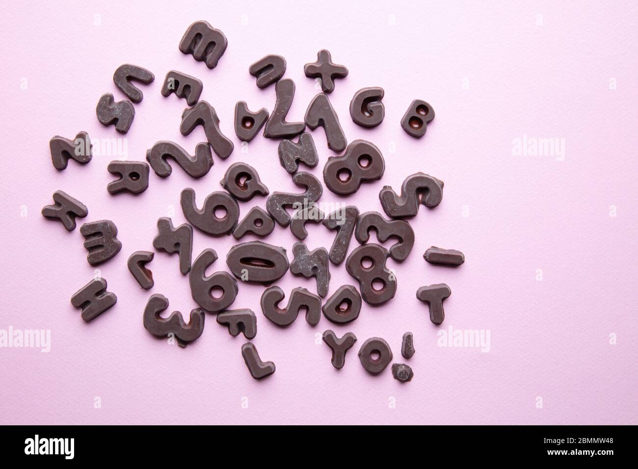 an artsy studio shot of chocolate letters and numbers against a pastel ...