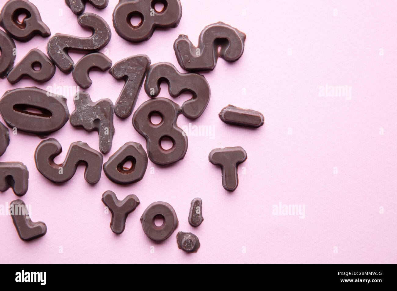 an artsy studio shot of chocolate letters and numbers against a pastel ...