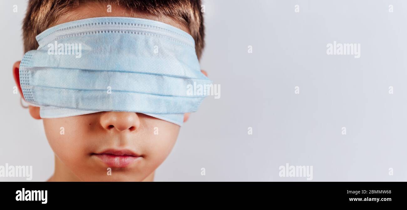 isolated blindfolded child with surgical mask over the eyes and bare ...