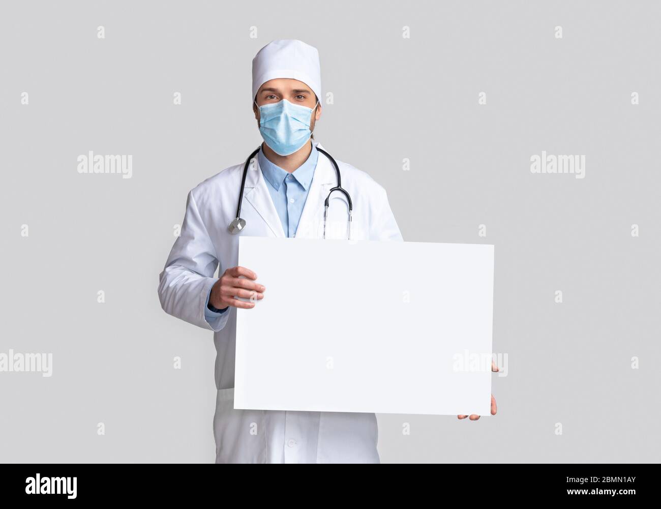 Doctor in protective mask holding blank warning sign Stock Photo - Alamy