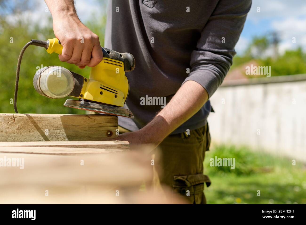 Unrecognizable man in the garden sanding wooden planks. DIY home ...
