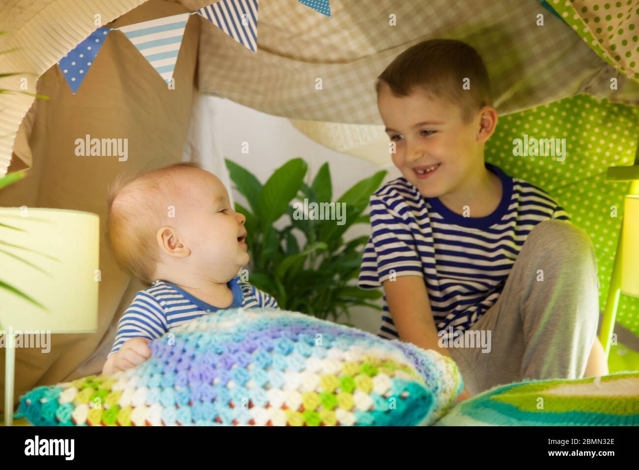 Two cute brothers play with a flashlight in a children's tent. 6 years ...