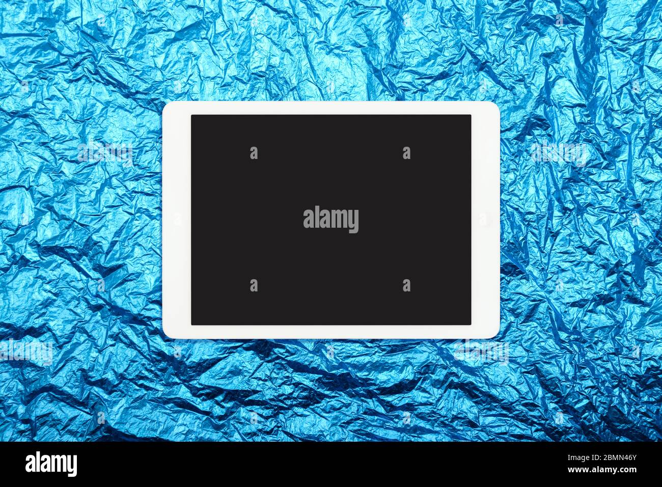 White touchpad with blank screen on electric blue crumpled foil texture ...