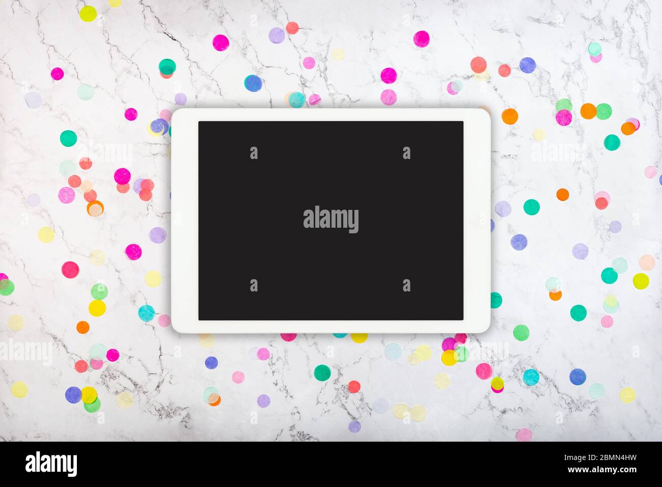 Flat lay of white touchpad with blank screen on colorful confetti ...