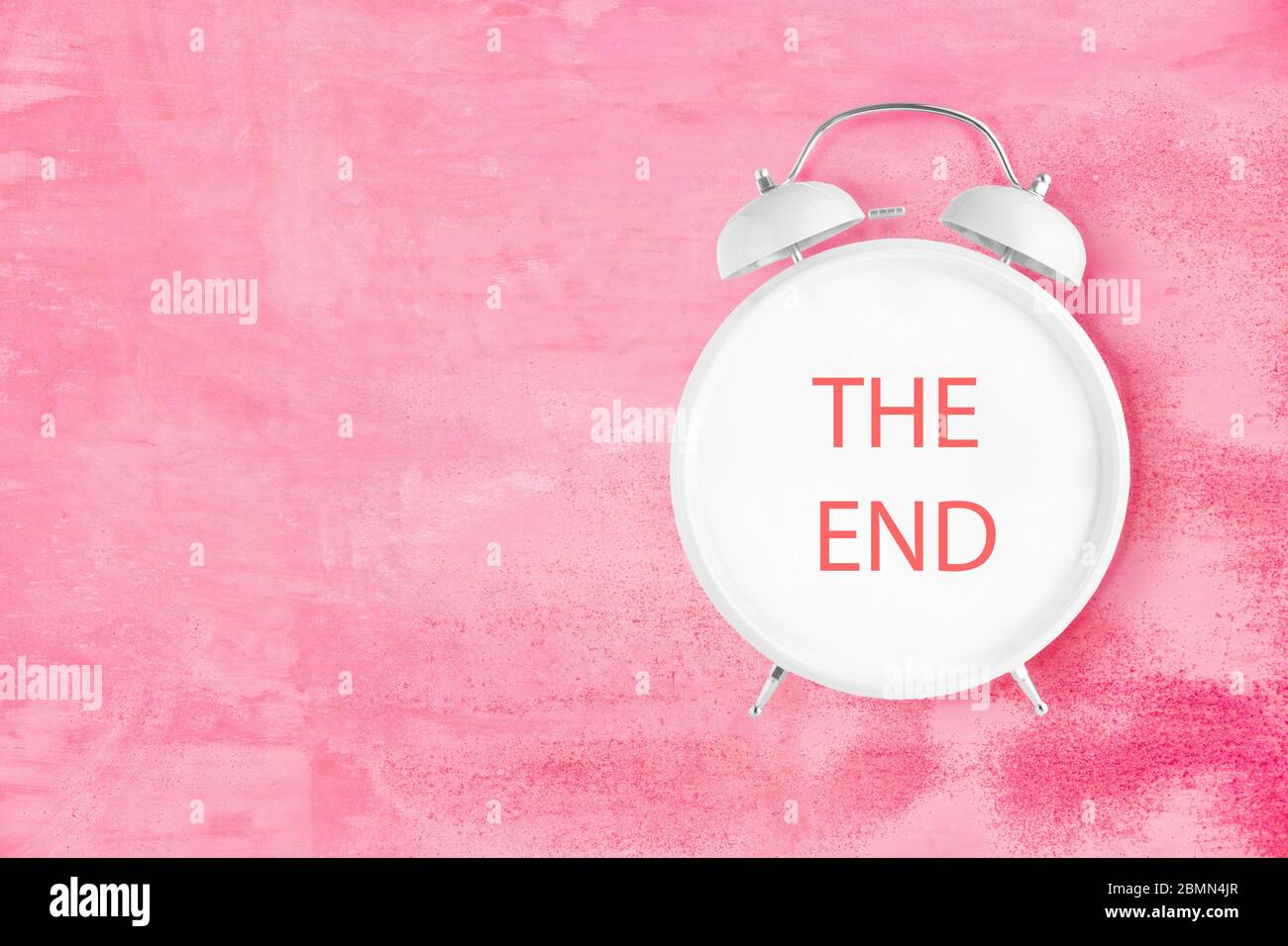 White alarm clock with THE END message on clock face on pink background ...
