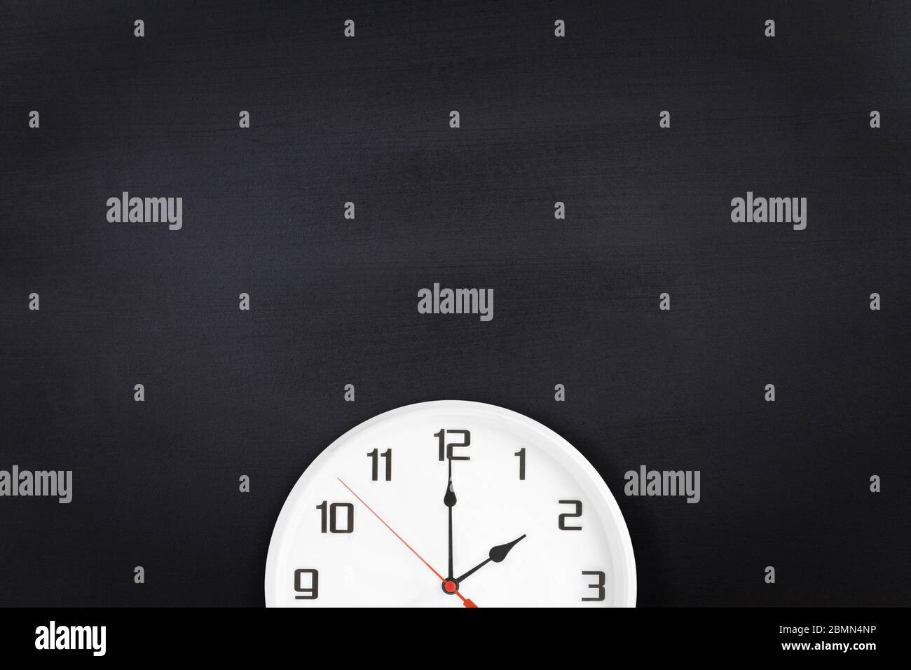 White wall clock on black chalkboard background. Space for your chalk ...