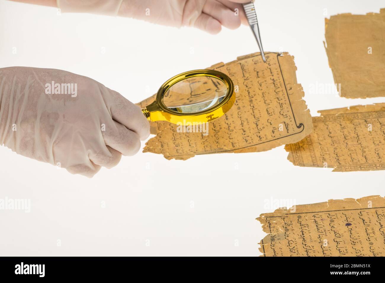 A researcher studies Arabic writing from the Koran using a magnifying ...