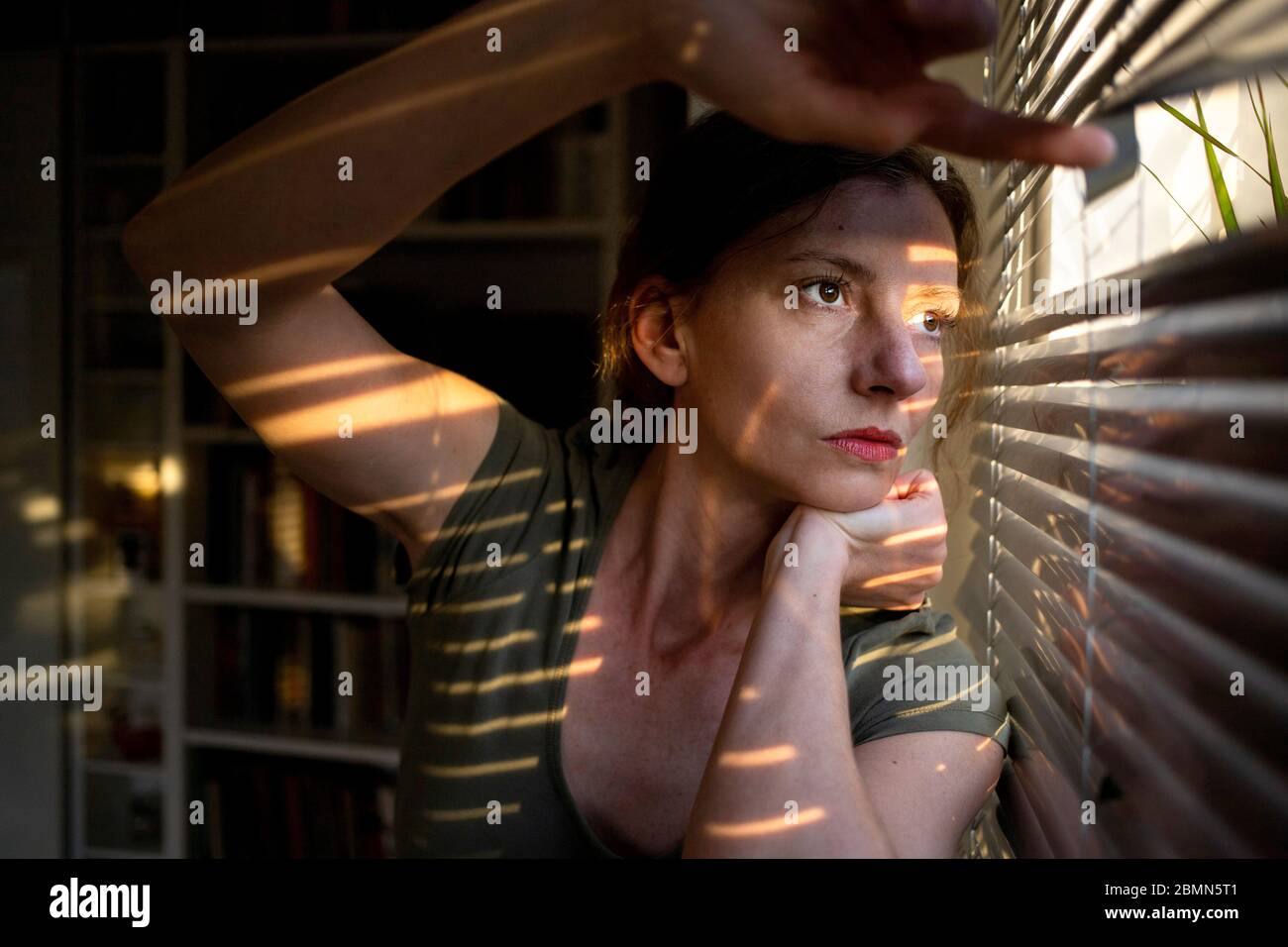 woman in home quarantine looking out on window thinking about future ...