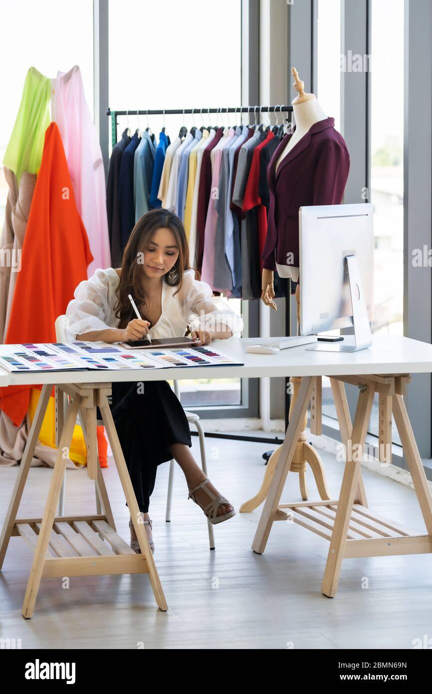 Young adult asian fashion designer drawing and sketching her work at ...