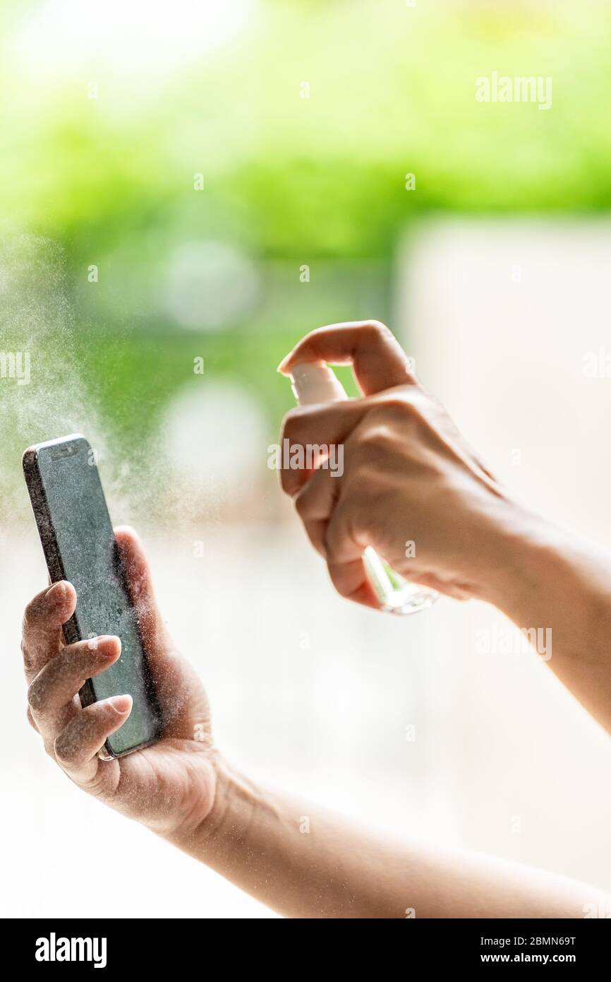 close-up cleaning mobile phone using alocohol spray from bottle ...