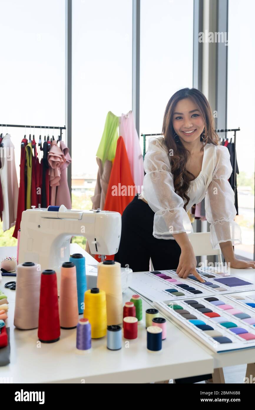 Portrait of young adult asian fashion designer working from home with ...