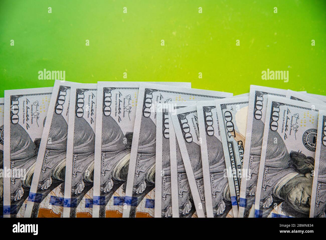 Stack of hundreds of dollars on bright green background with copy space ...