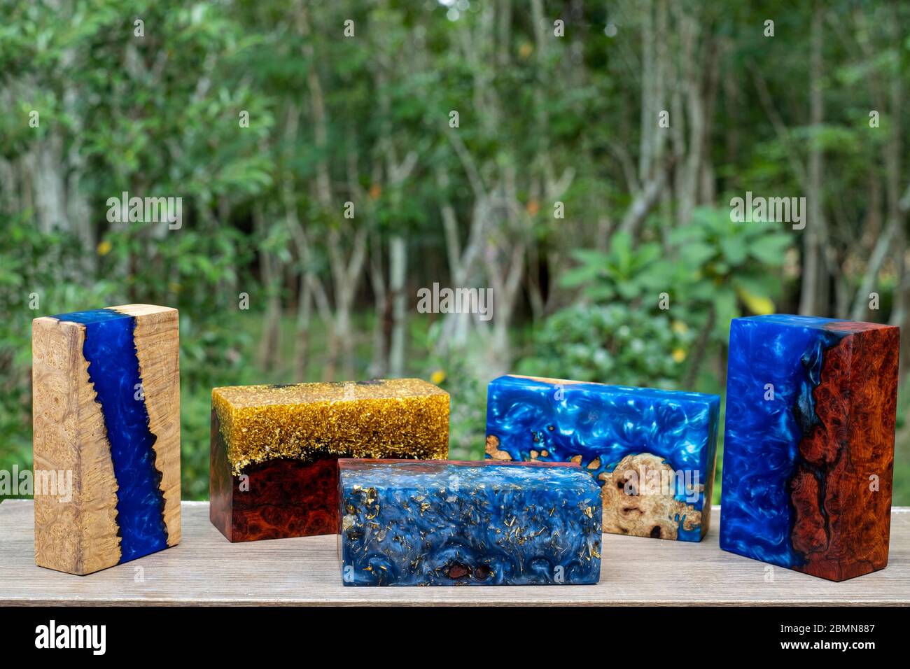 Casting epoxy resin burl wood cube on table at green blured background ...