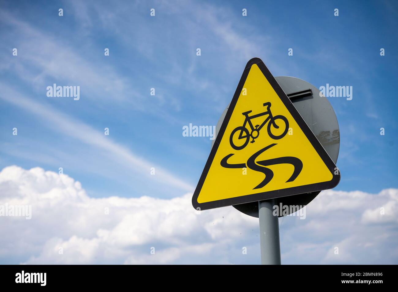 A yellow sign warning against cyclists against a blue sky on a cycle ...