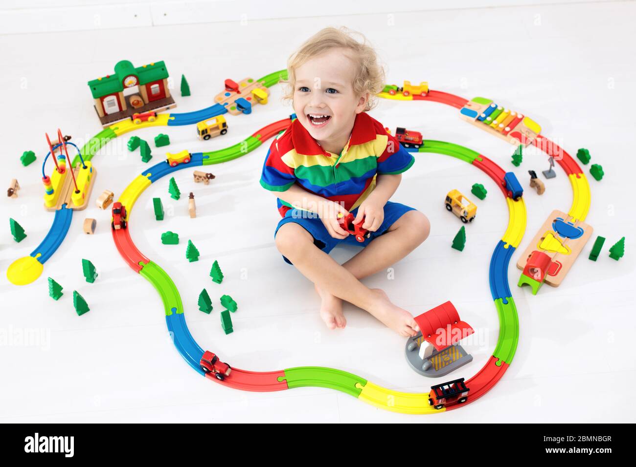 Kids play with toy train railway. Child playing with colorful rainbow ...
