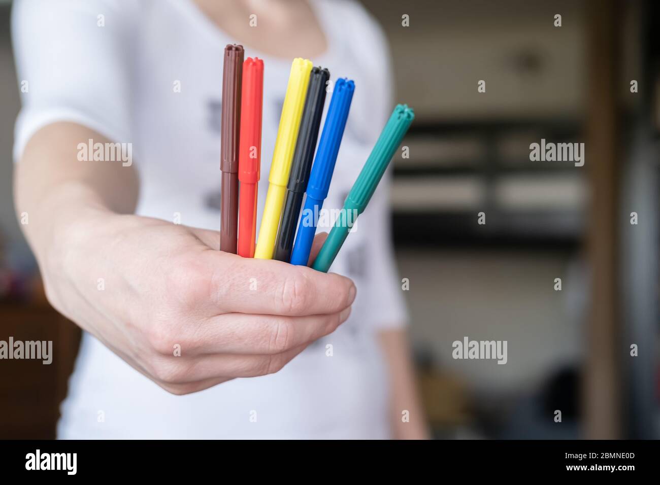Colored markers in a female hand, on a blurred background, in natural ...