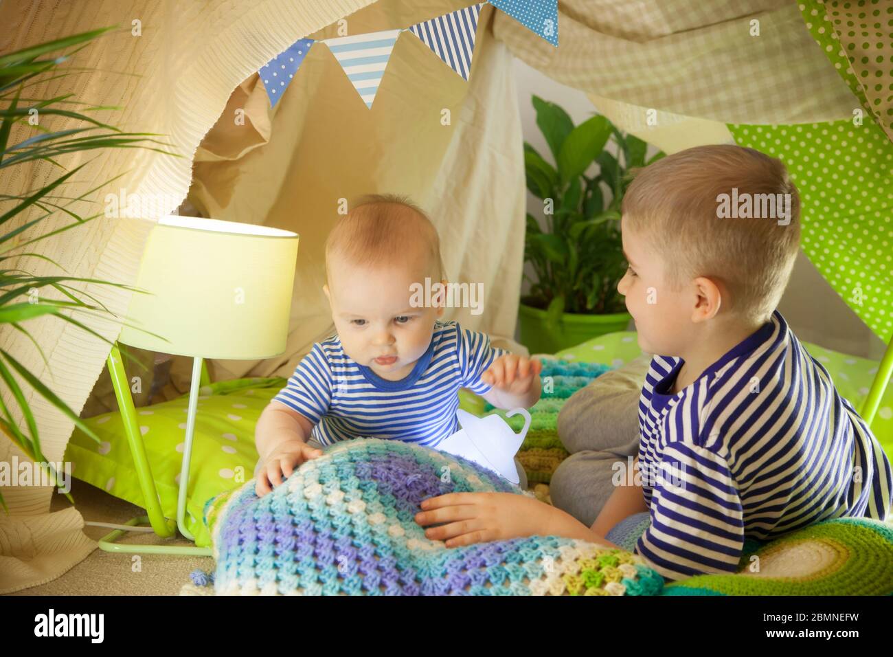 Two cute brothers play with a flashlight in a children's tent. 6 years ...