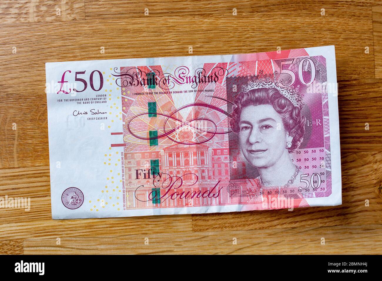A Fifty pound note laying flat on an oak table, £50 cash banknote Stock ...
