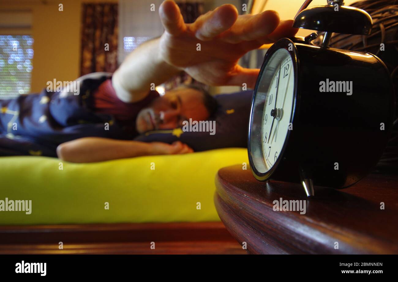 Morning wake up in the bedroom. The man sleep and turns the alarm off ...