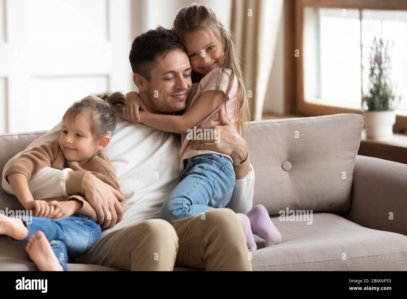 Loving young father cuddling with two little daughters Stock Photo - Alamy
