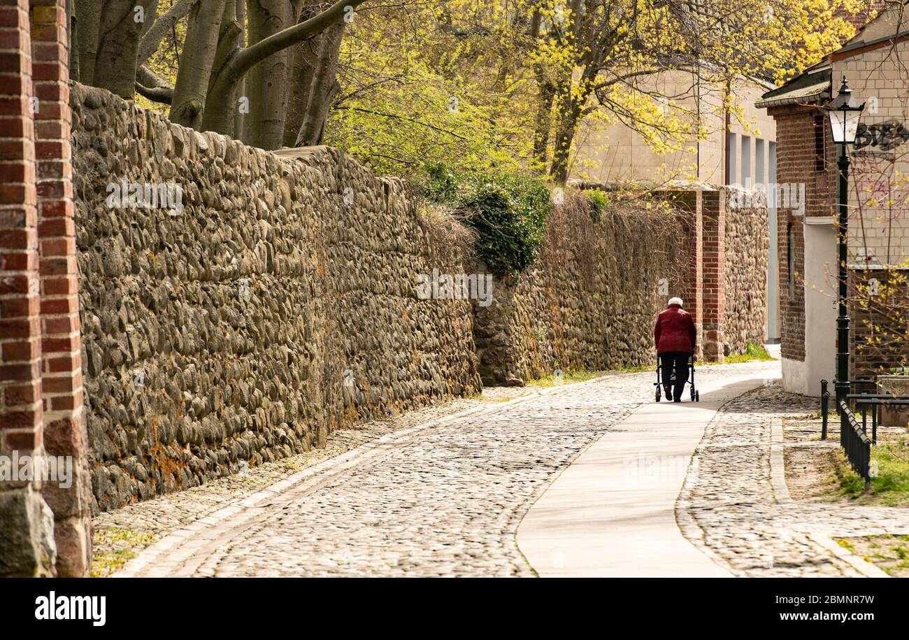 Bernau, Germany. 15th Apr, 2020. A woman walks an alley along the ...