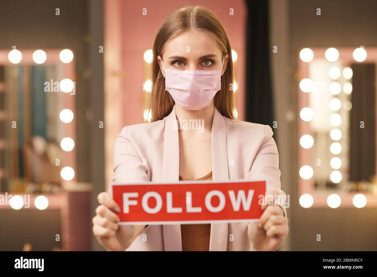 Waist up portrait of beautiful young woman wearing pink face mask and ...