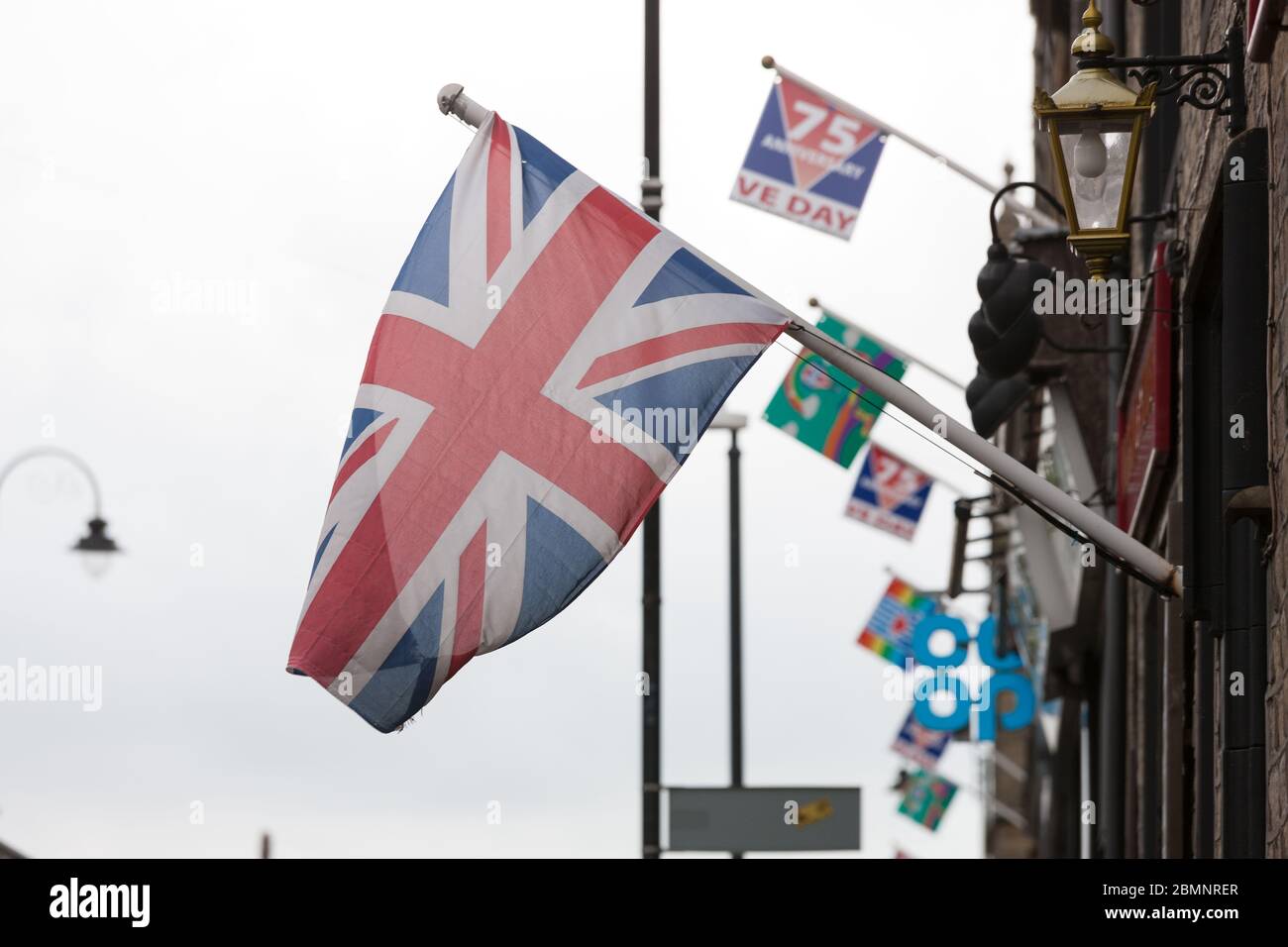 Meltham, UK - May 5 2020: The Union Flag flies next to VE day and NHS ...