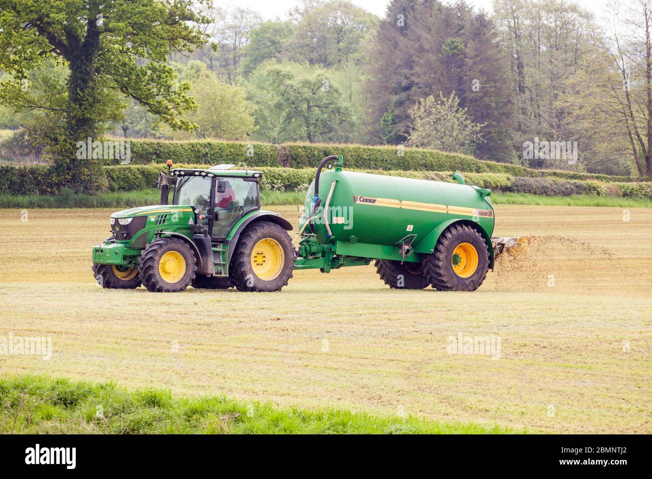 Farmer spreading slurry on a farm field driving a John Deere 6930 ...