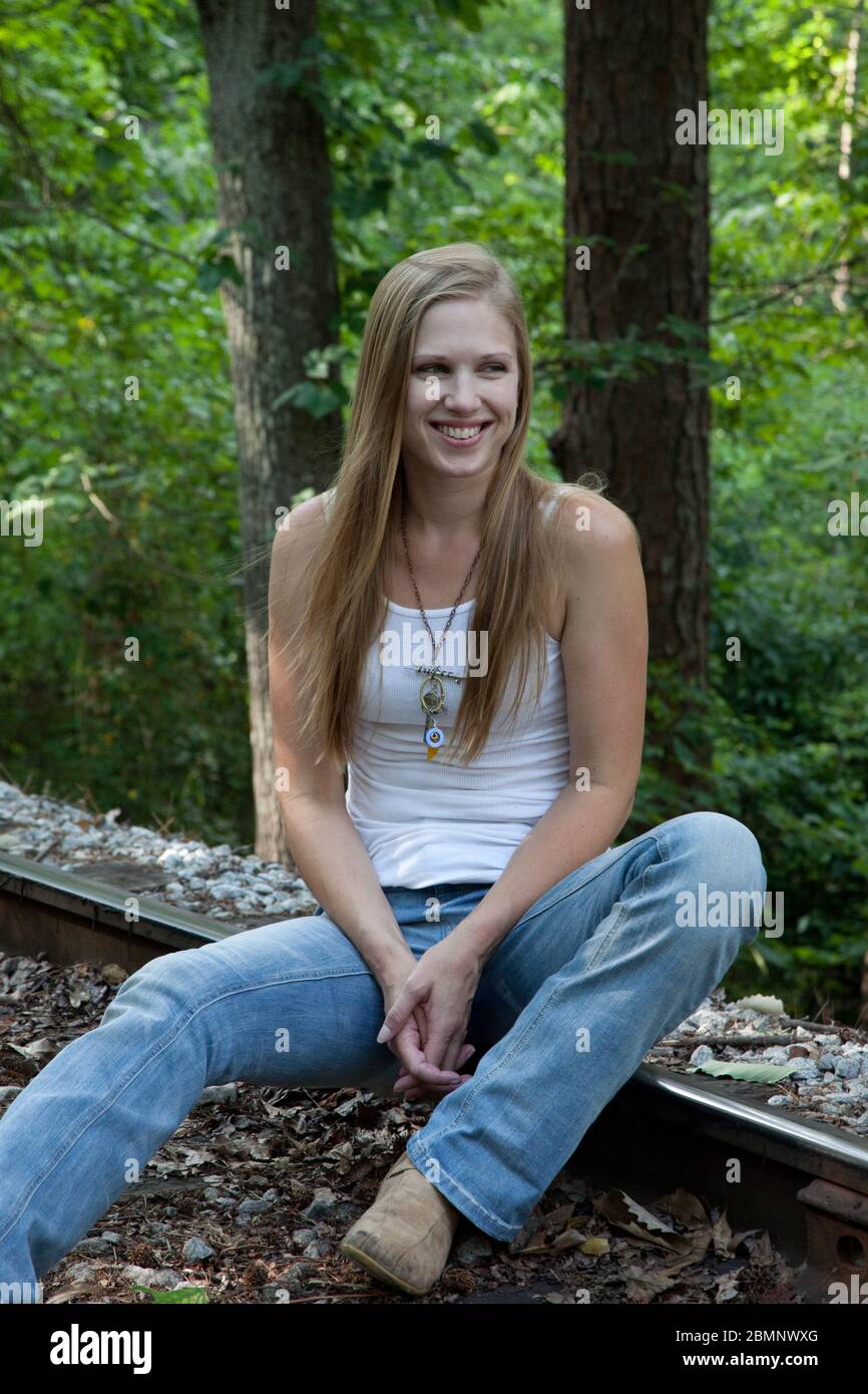 Pretty Blond sitting on Railroad Tracks with a smile Stock Photo - Alamy